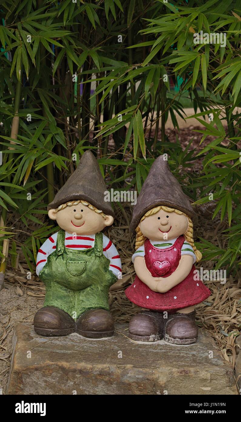 Two garden gnomes, a boy and a girl, against a garden background of ...