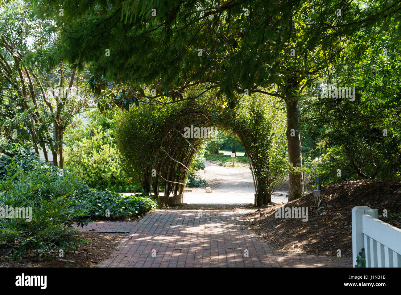 Brick path through arch in the garden Stock Photo - Alamy