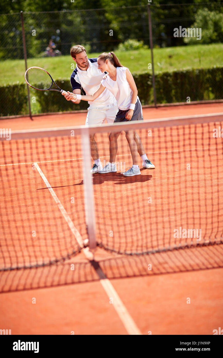 Girl with tennis trainer practicing serve on tennis court Stock Photo ...