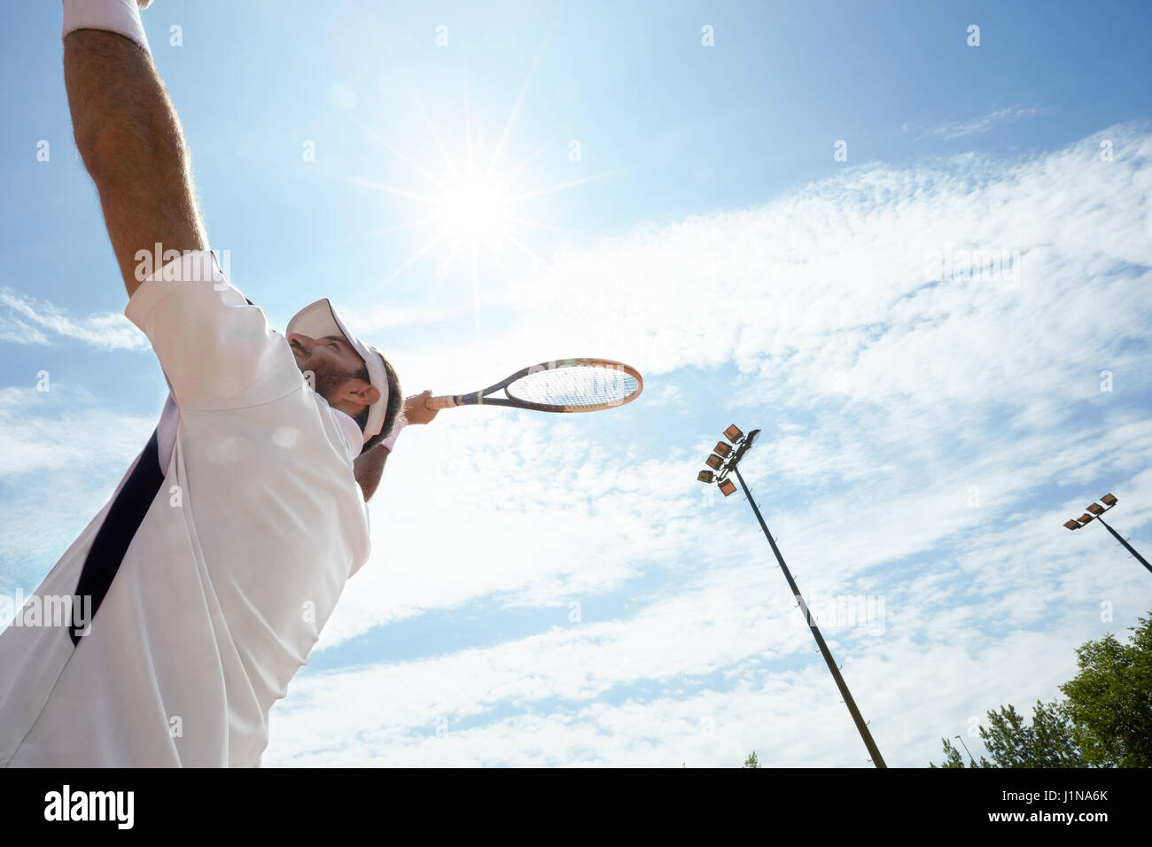 Tennis player serving ball on tennis court on shinny day Stock Photo ...