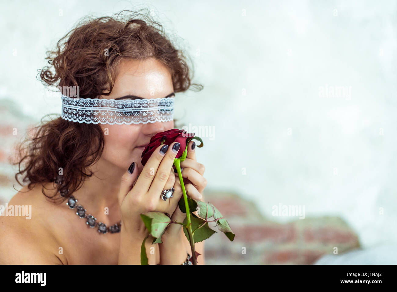 Beautiful woman smells red rose Stock Photo - Alamy