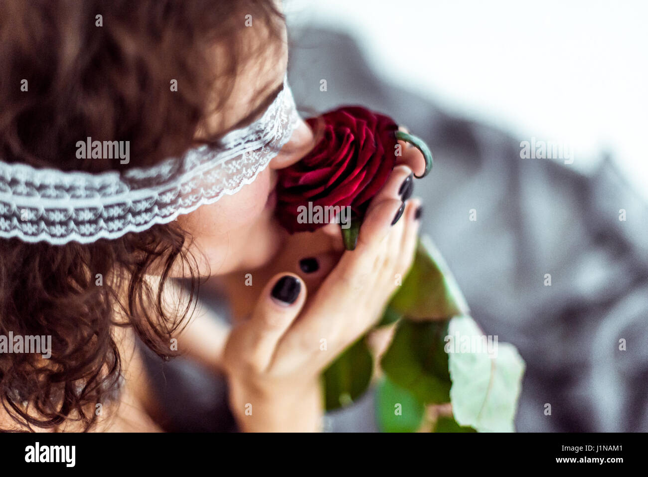 Beautiful woman smells red rose Stock Photo - Alamy