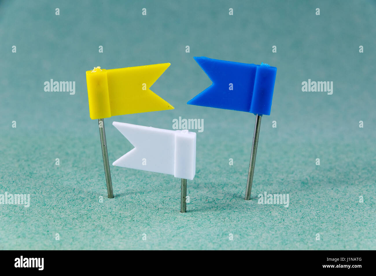Yellow, Blue and White flag pins on a green background Stock Photo - Alamy