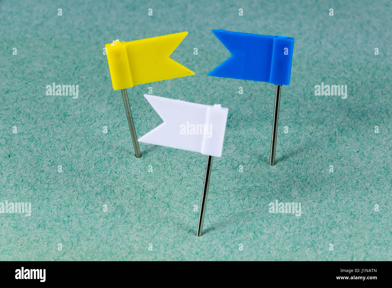 Yellow, Blue and White flag pins on a green background Stock Photo - Alamy