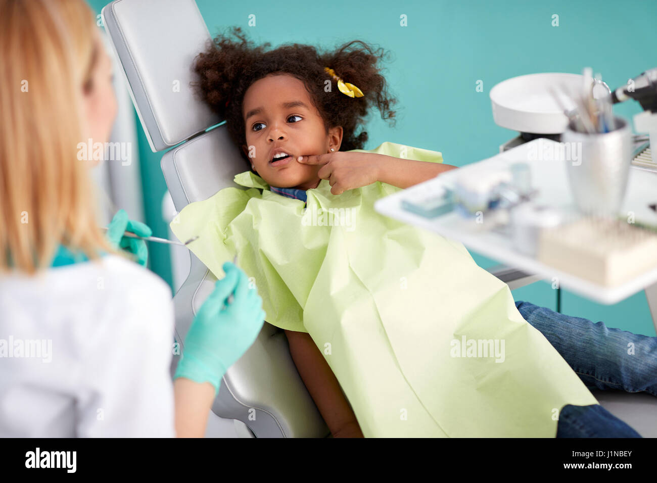 Very cute black kid in dental chair showing aching tooth Stock Photo ...