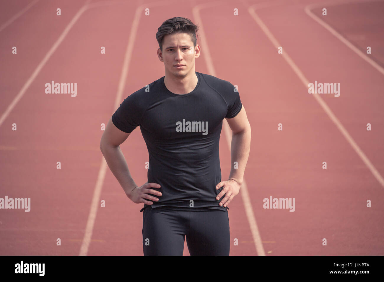 one young man, runner posing, red running tracks, outdoors, black ...