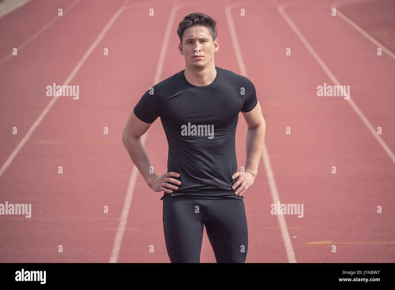 one young man, runner posing, red running tracks, outdoors, black ...