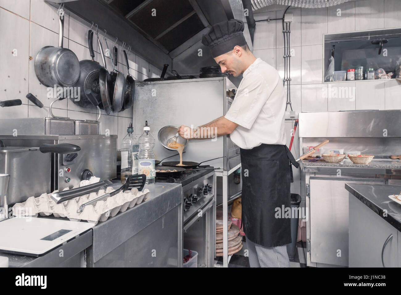 one young adult man, chef beaten eggs pan cooking, professional ...