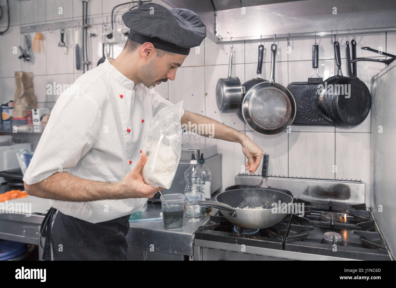 one young adult man professional chef cooking pasta dish Parmesan, pan ...