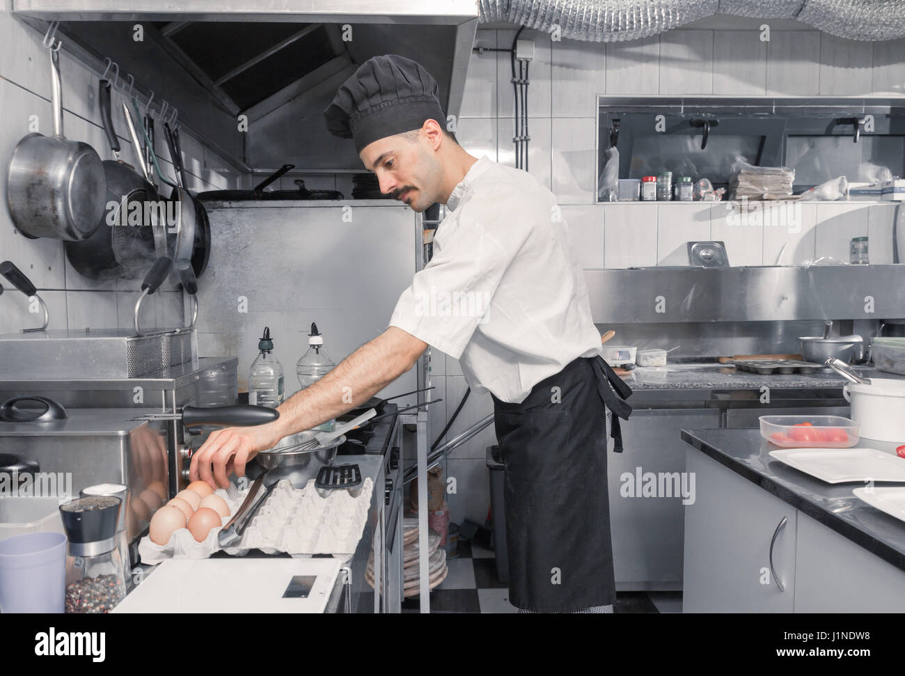 one young man chef picking eggs, professional commercial kitchen Stock ...