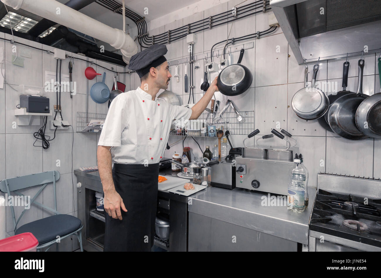 one young adult man, professional chef, commercial kitchen, pans ...