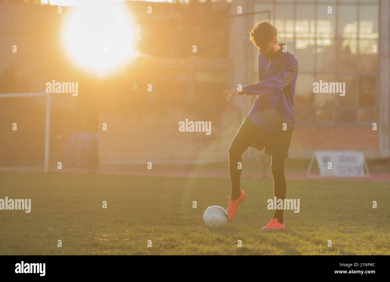young football player shooting soccer ball. grass field sun, sunny ...