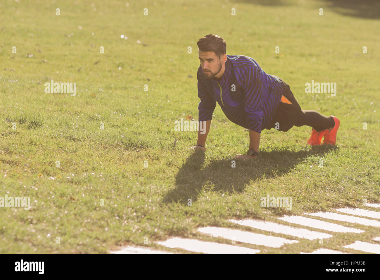young man athlete football player, push ups exercise. green grass ...