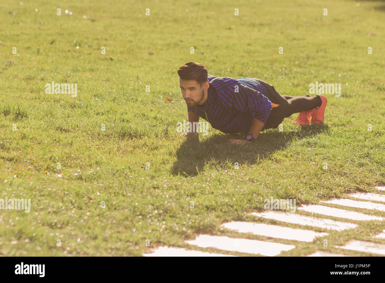 young man athlete football player, push ups exercise. green grass ...