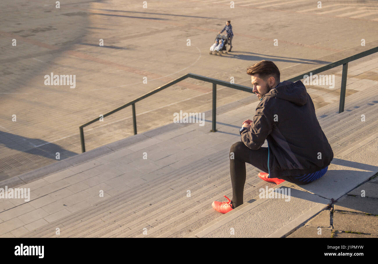 young man, athlete, football player, soccer player, sitting stairs ...