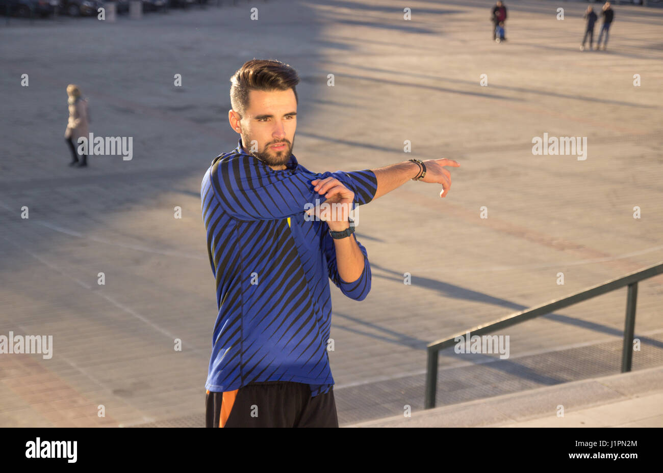 young man athlete upper body shot, stretching. sunny day stairs steps ...