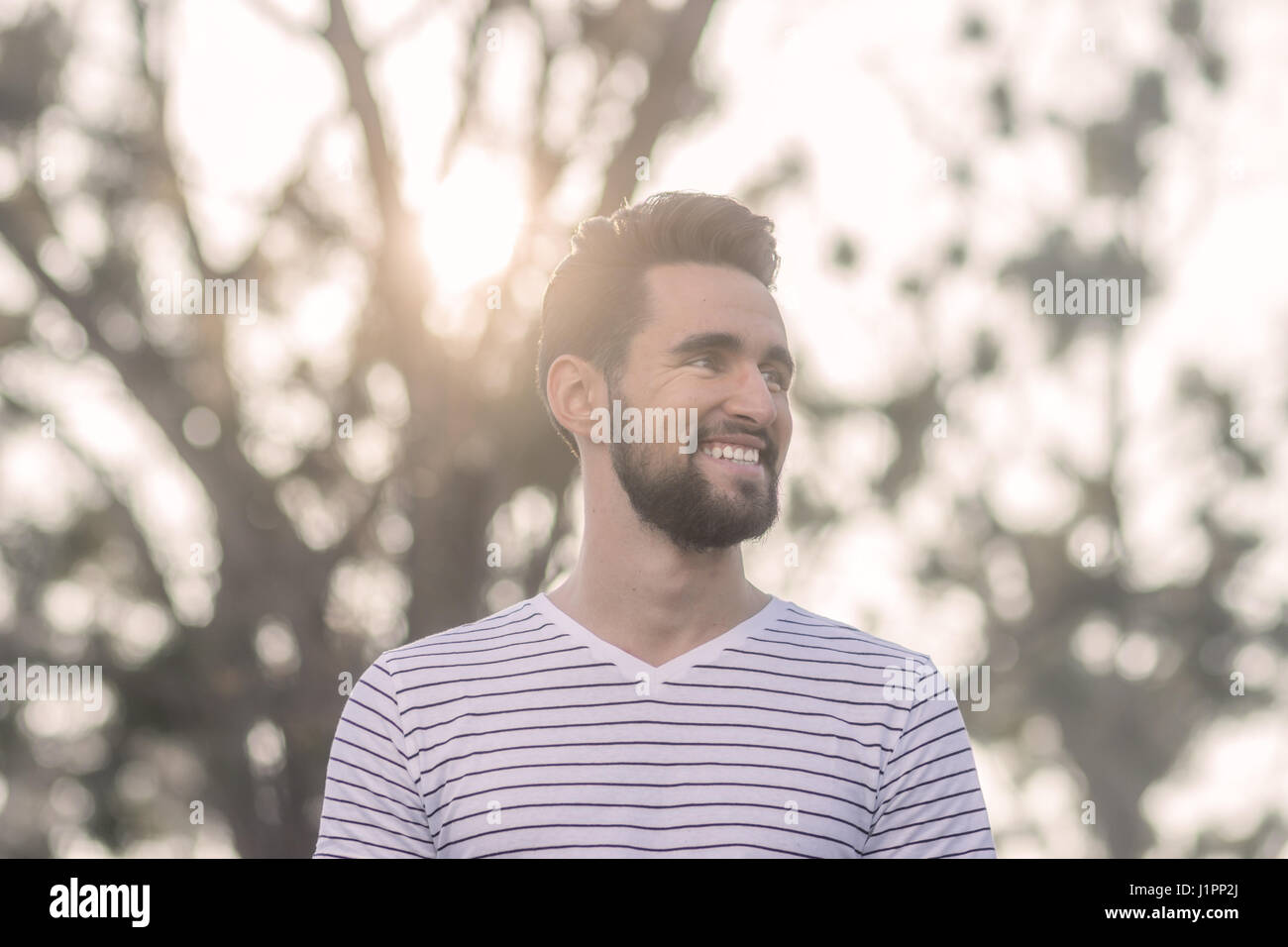 One smiling young adult man, looking sideways, head face. Wearing t ...