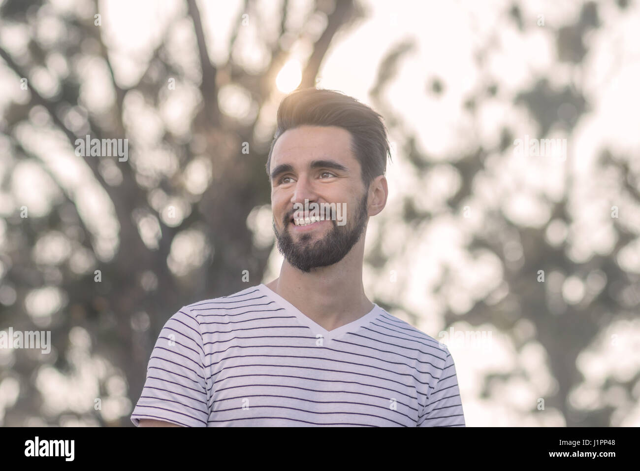 One smiling young adult man, looking sideways, head face. Wearing t ...
