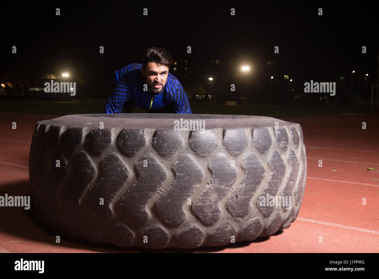Athlete moving tire, exercise. Outdoors, dark, night Stock Photo - Alamy