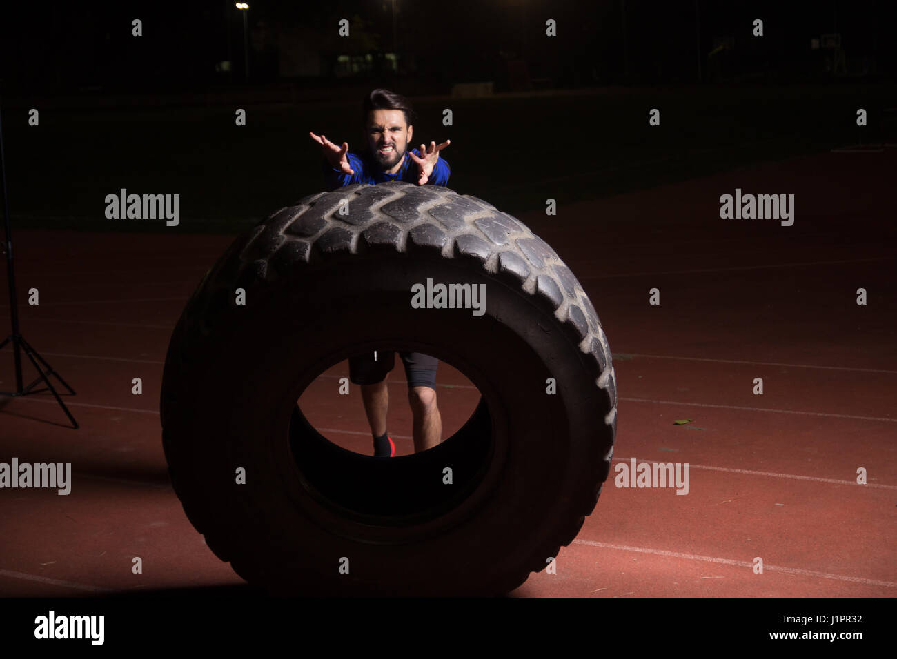Young adult man, athlete exercise, throwing tire, exercise. Outdoors ...