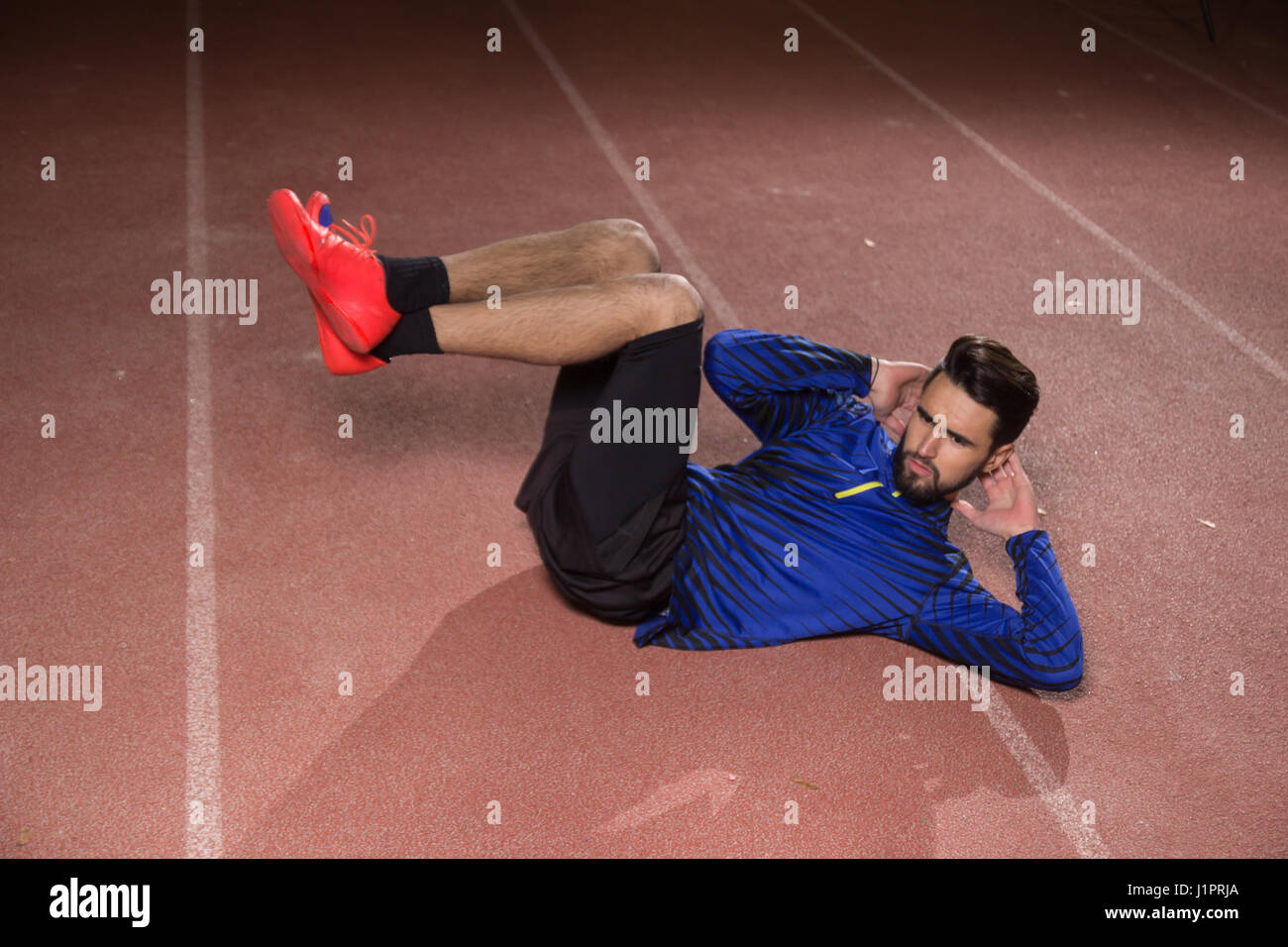 One young adult man, core side abs exercise, athlete, running tracks ...