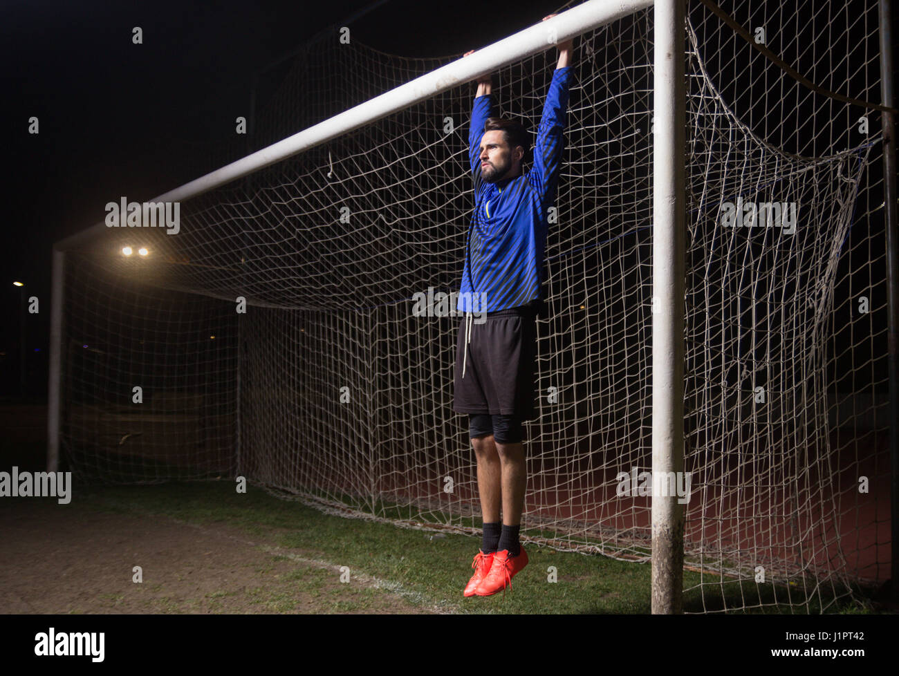 young adult man, football player, soccer player, stretching goal post ...
