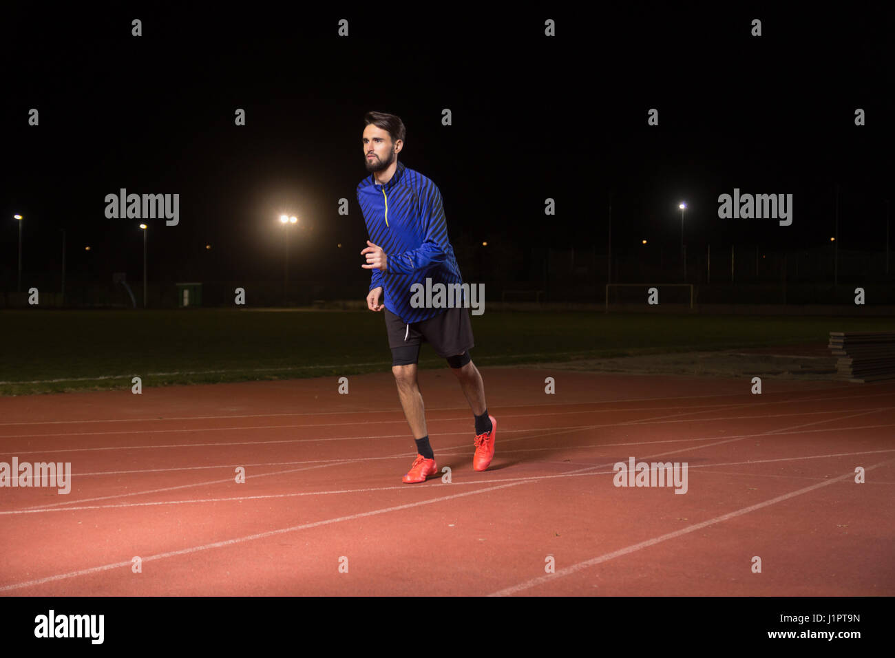 One young adult man, runner, running tracks. Dark night time Stock ...