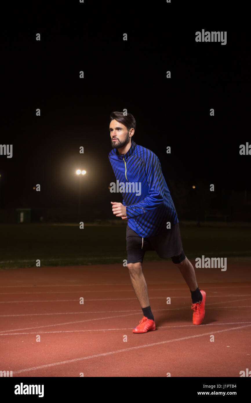 One young adult man, runner, running tracks. Dark night time Stock ...
