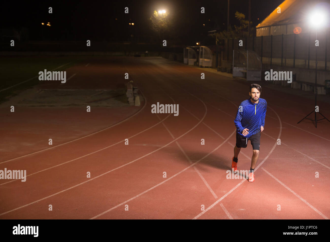 One young adult man, runner. Running tracks. Dark night time Stock ...
