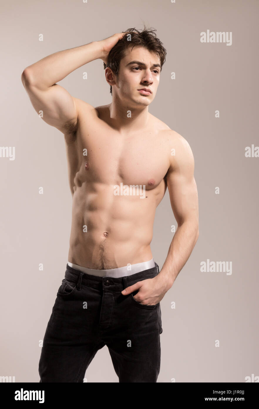 Young adult man, muscular fit, posing, looking sideways. Wearing jeans ...