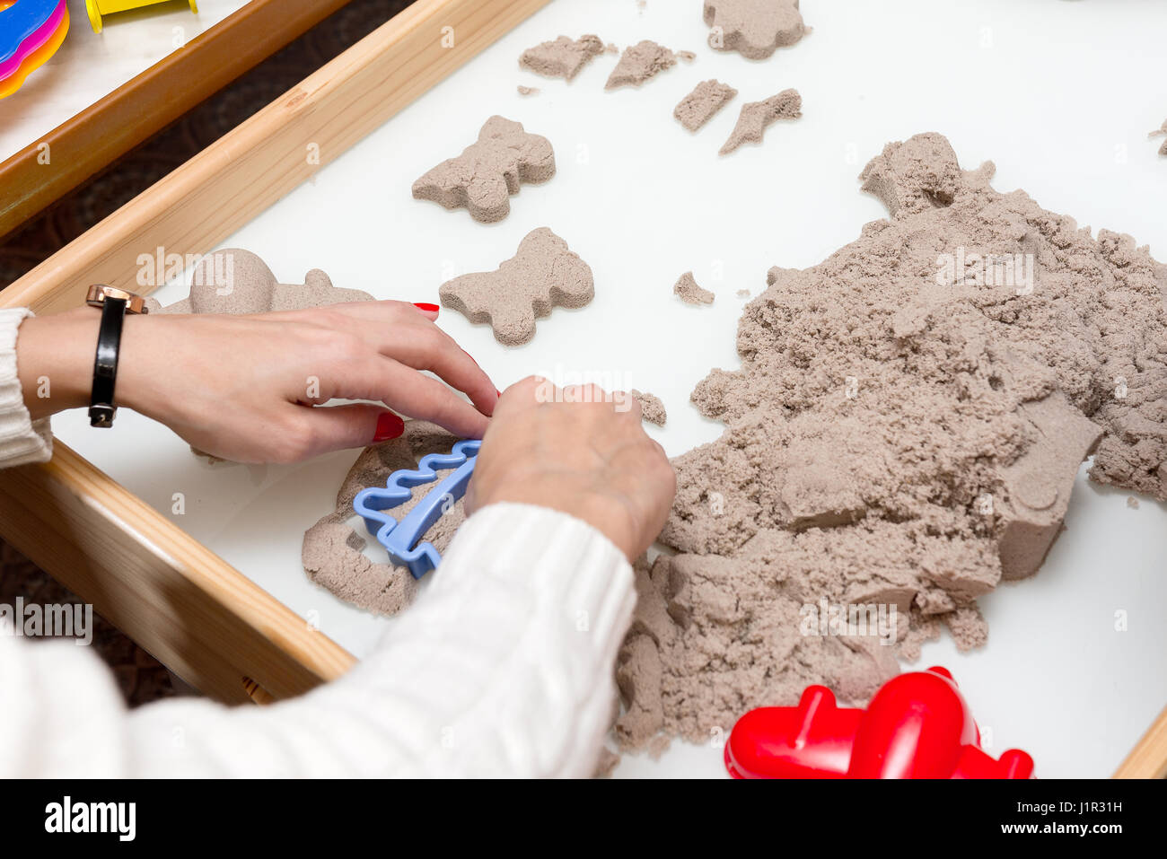 Wet sand creating shapes in the classroom with a child Stock Photo - Alamy