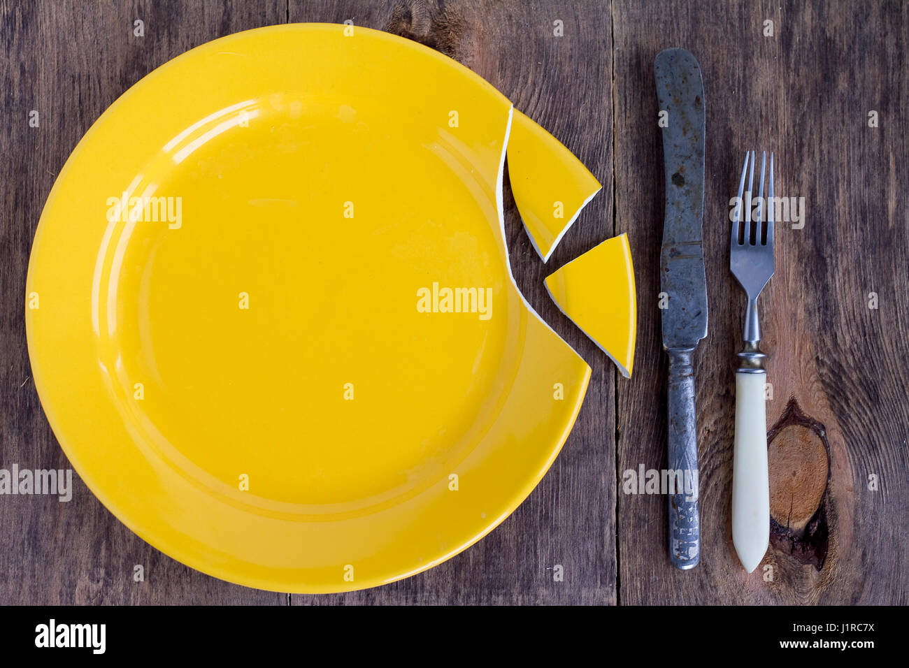 Broken yellow plate and Cutlery on wooden background Stock Photo - Alamy