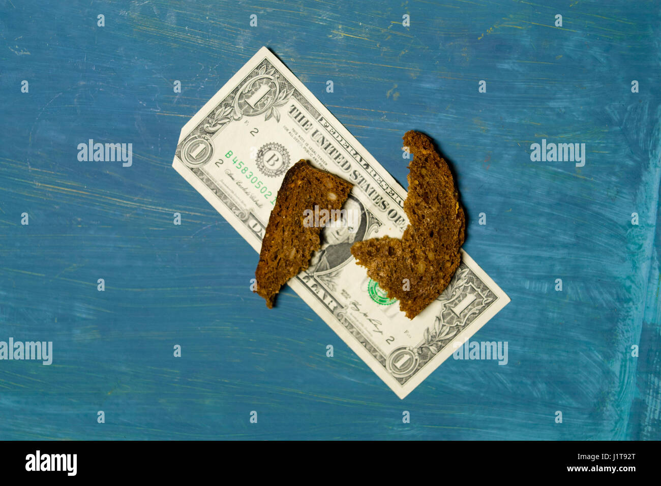 One dollar and bread laid on a painted table, overhead shot, concept of ...