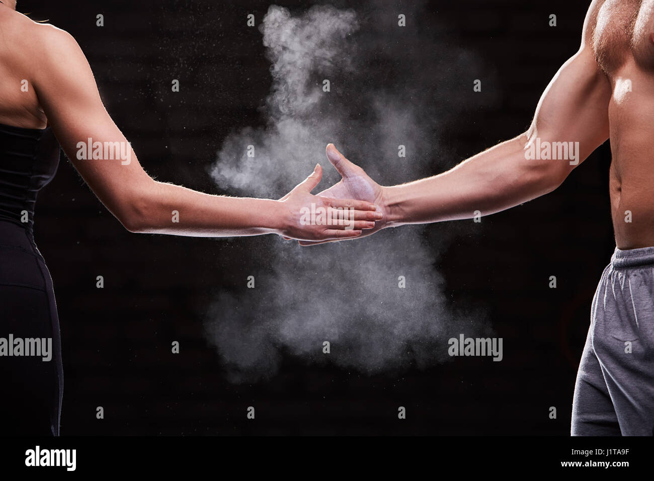 Cropped image of hands of athlete muscular man and woman against dark ...