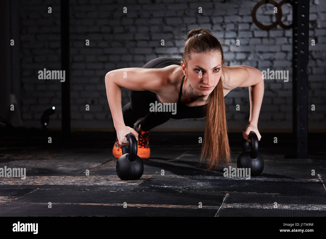 Young beautiful sporty woman in the black sportwear doing a pushups ...