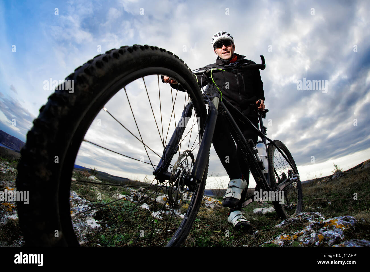 Bottom view photo of cyclist in the black sportwear standing with his ...