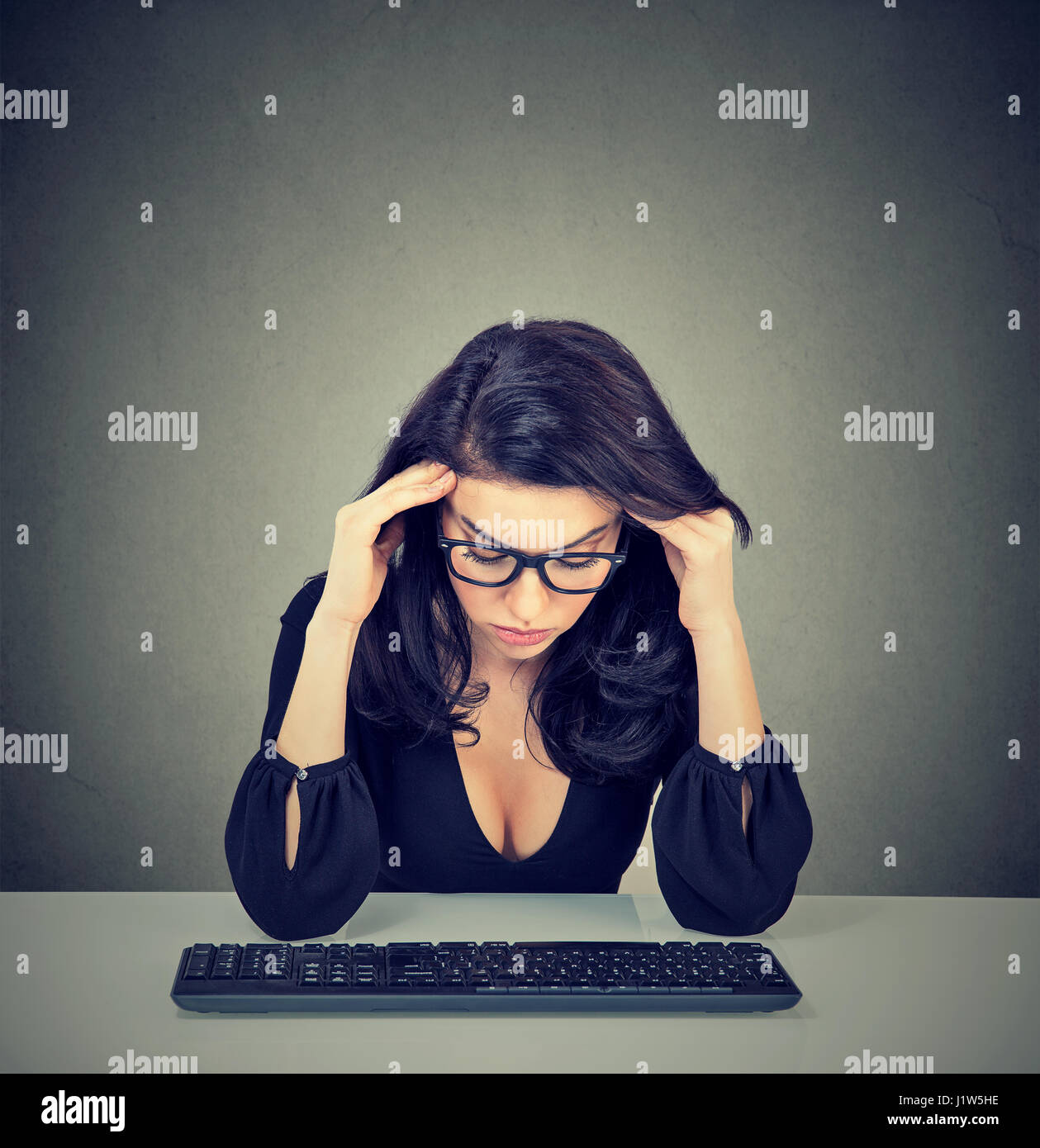 Overworked young bored woman sitting at desk in front of her computer ...