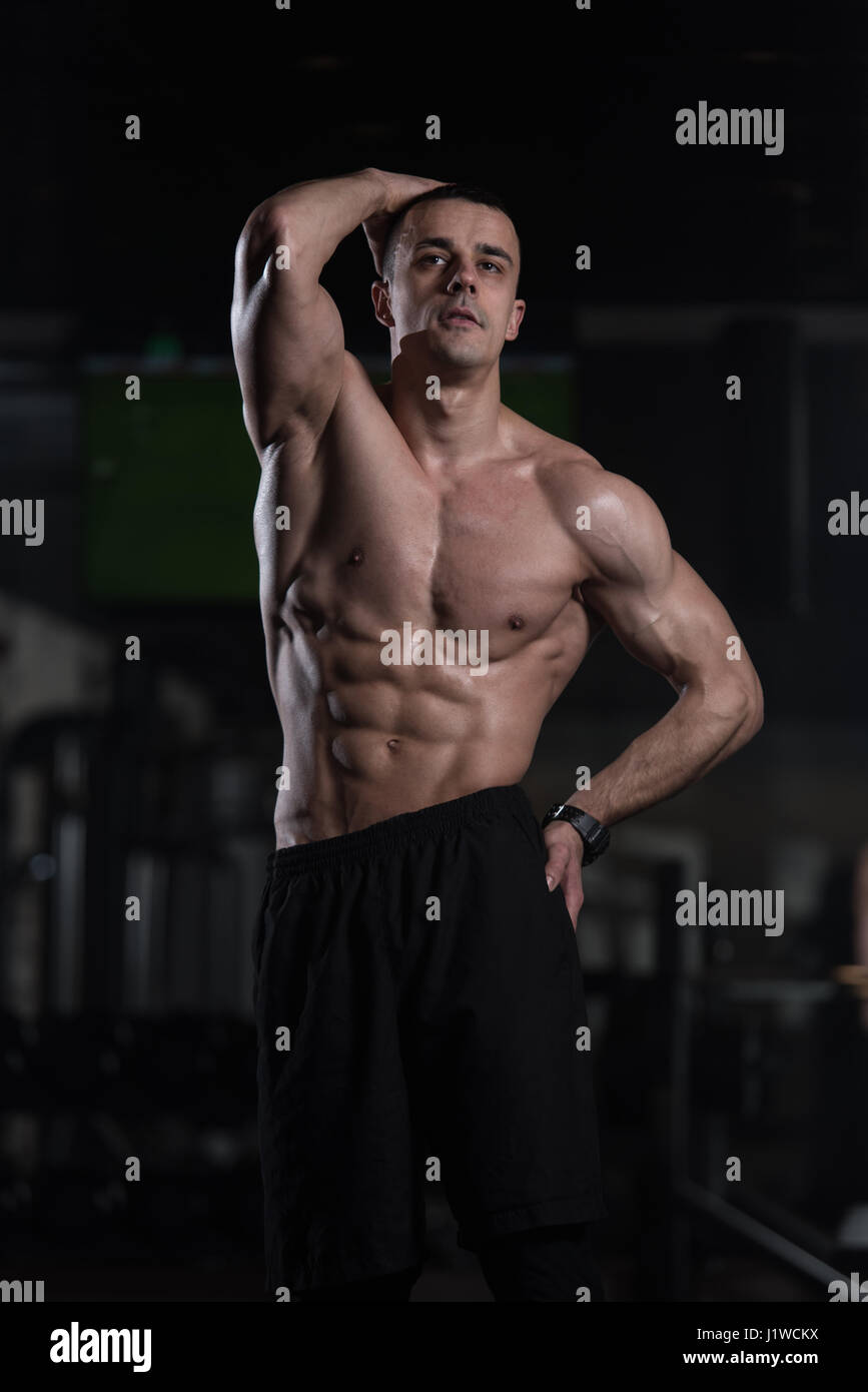 Handsome Man Standing Strong In A Modern Gym And Flexing Muscles ...