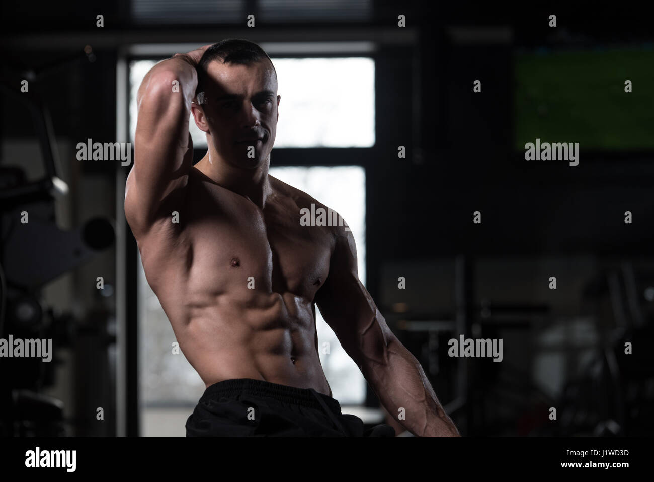 Handsome Man Standing Strong In A Modern Gym And Flexing Muscles ...