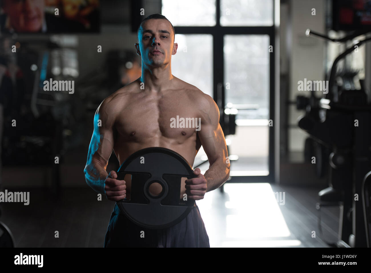 Young Man Exercising Abdominal Muscles With Weights In A Modern Fitness ...