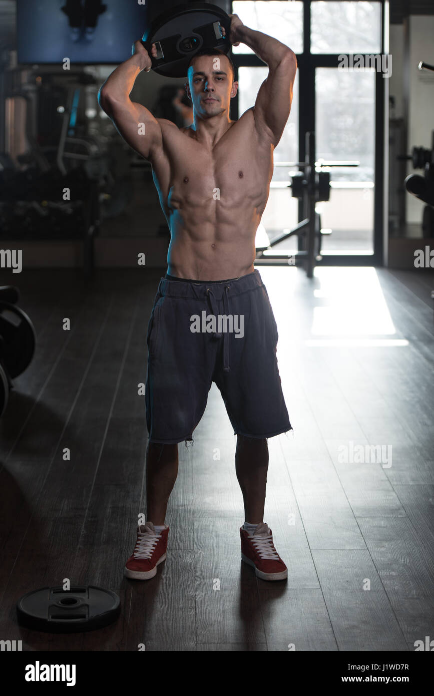 Young Man Exercising Abdominal Muscles With Weights In A Modern Fitness ...