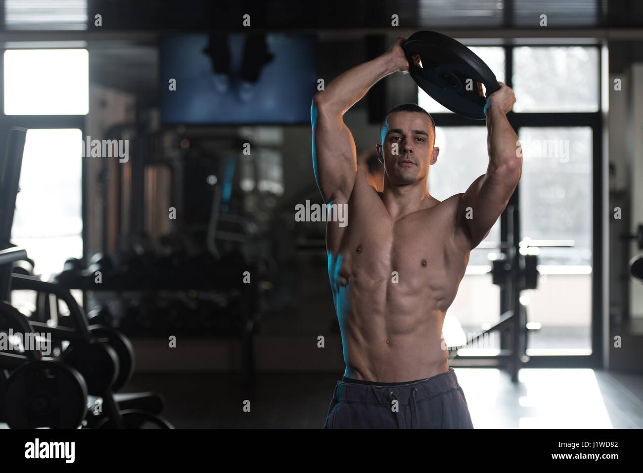 Muscular Man Exercising Abdominal Muscles With Weights In A Modern ...