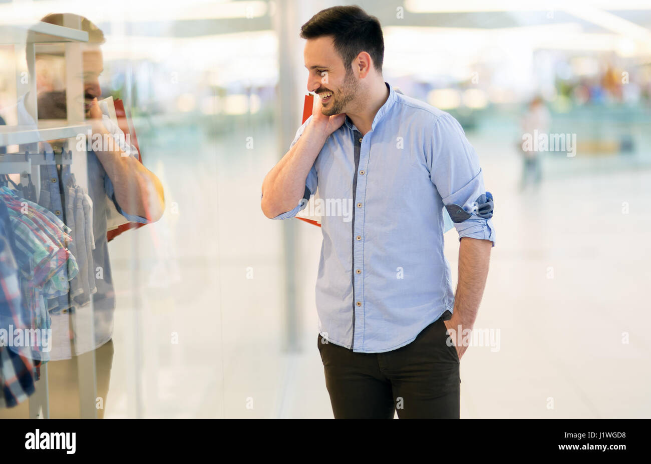 Handsome man shopping for clothes in shopping mall Stock Photo - Alamy