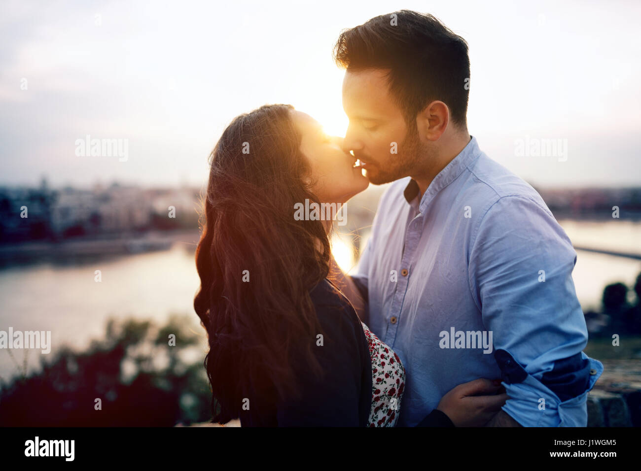 Romantic couple in love cuddling and kissing outdoors during sunset ...