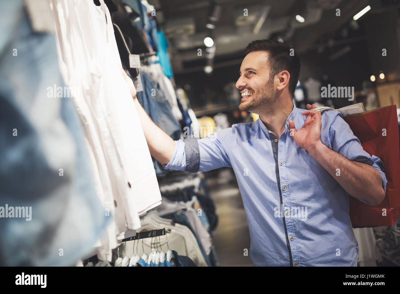 Handsome man shopping for new clothes in store Stock Photo - Alamy