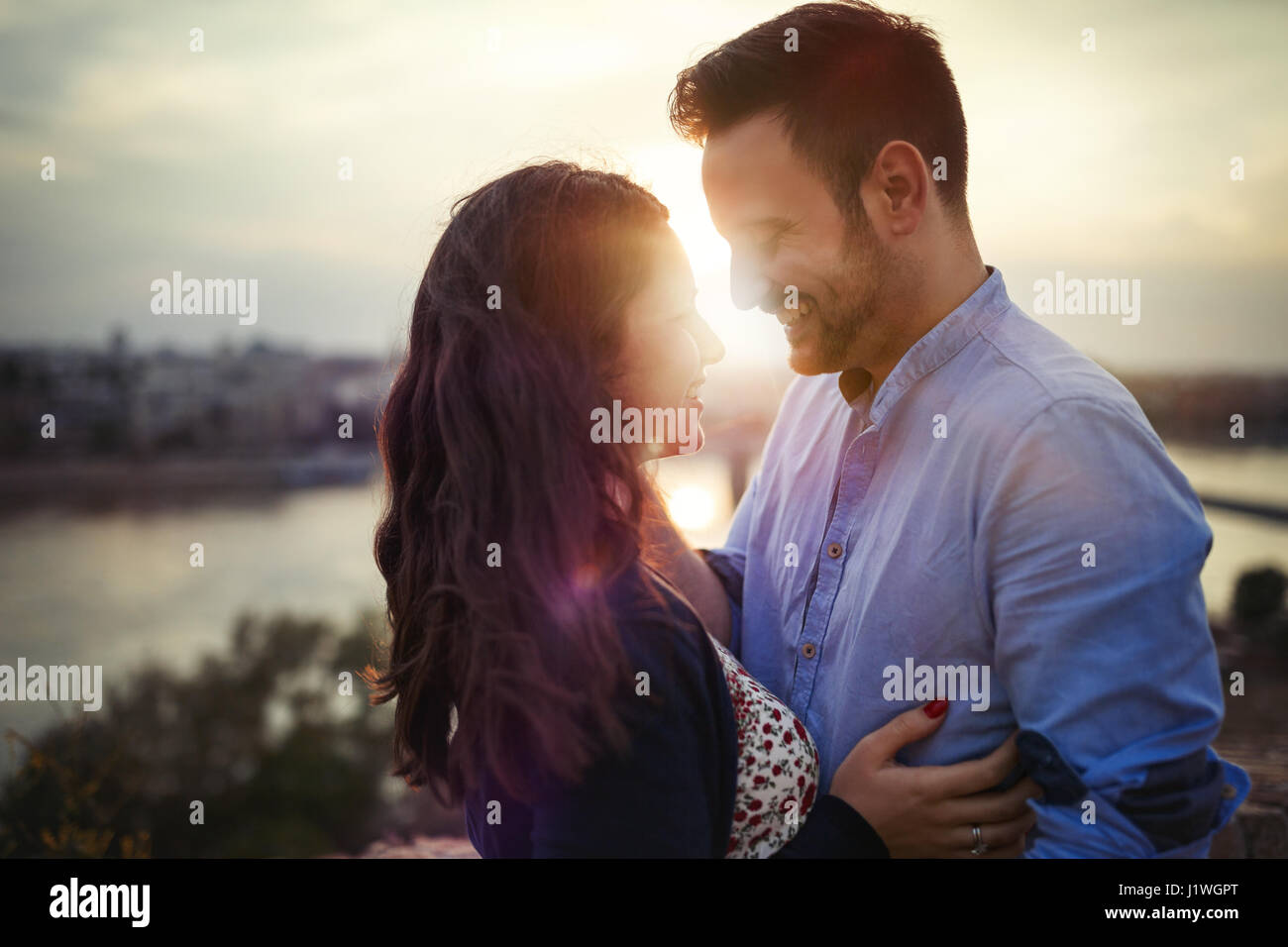 Romantic couple in love cuddling and kissing outdoors during sunset ...