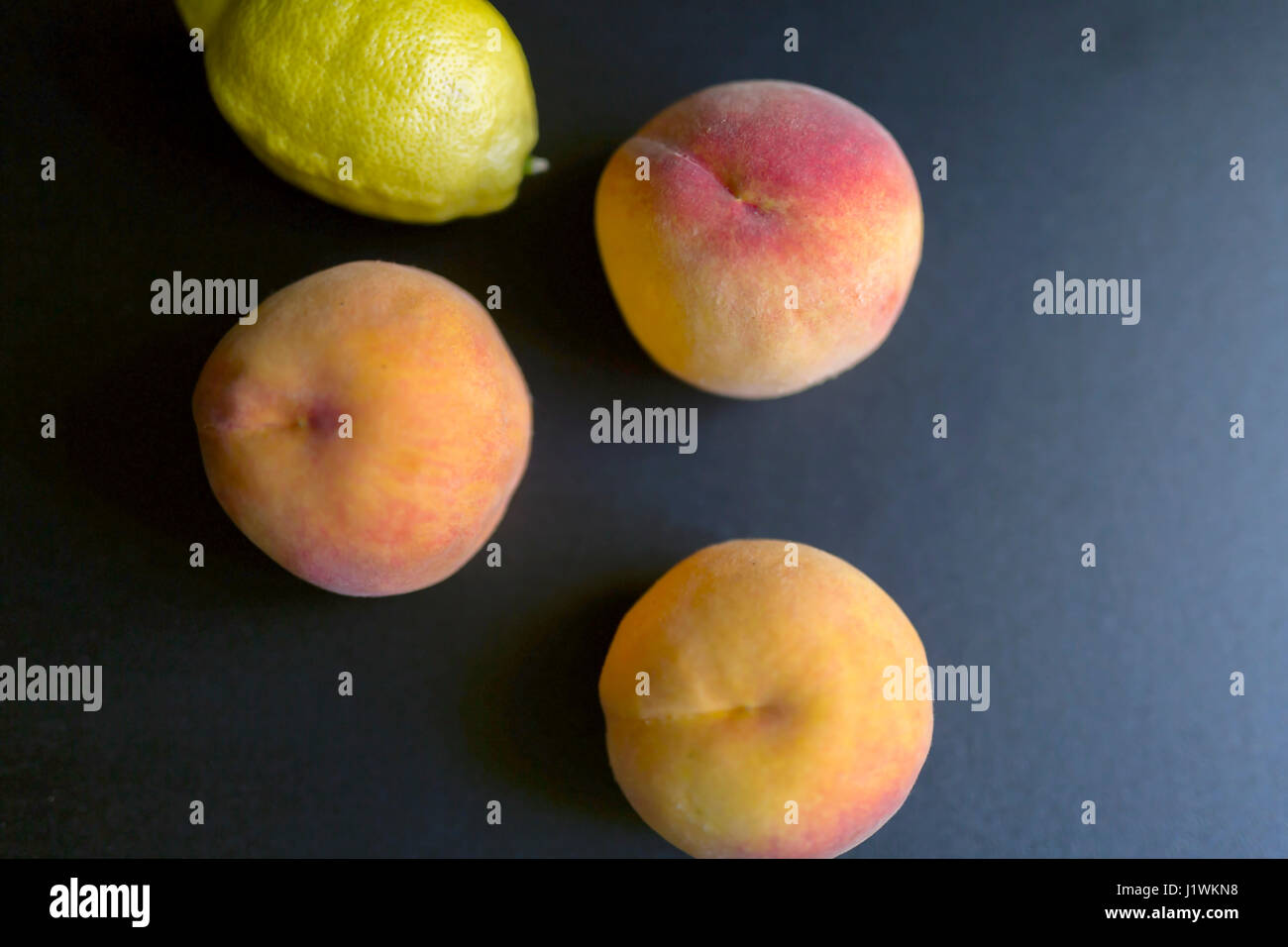 Fresh peaches and a lemon on a black background, top view Stock Photo ...
