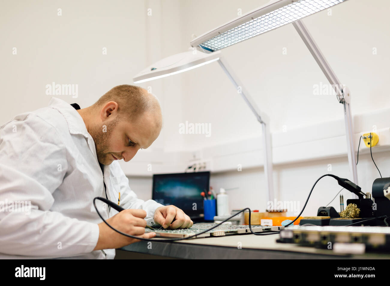 Technician fixing motherboard by soldering chips Stock Photo - Alamy