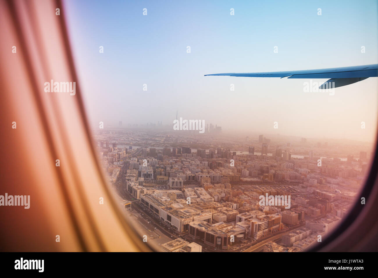 Beautiful evening cityscape of Dubai in haze through aircraft window ...