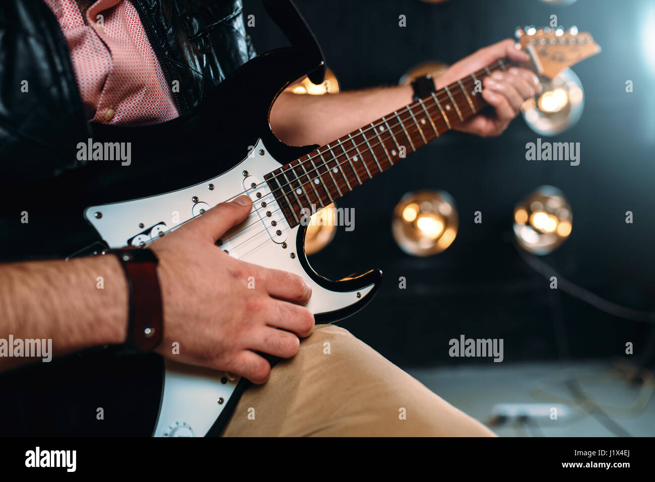Male guitarist hands performing music on the stage with the decorations ...